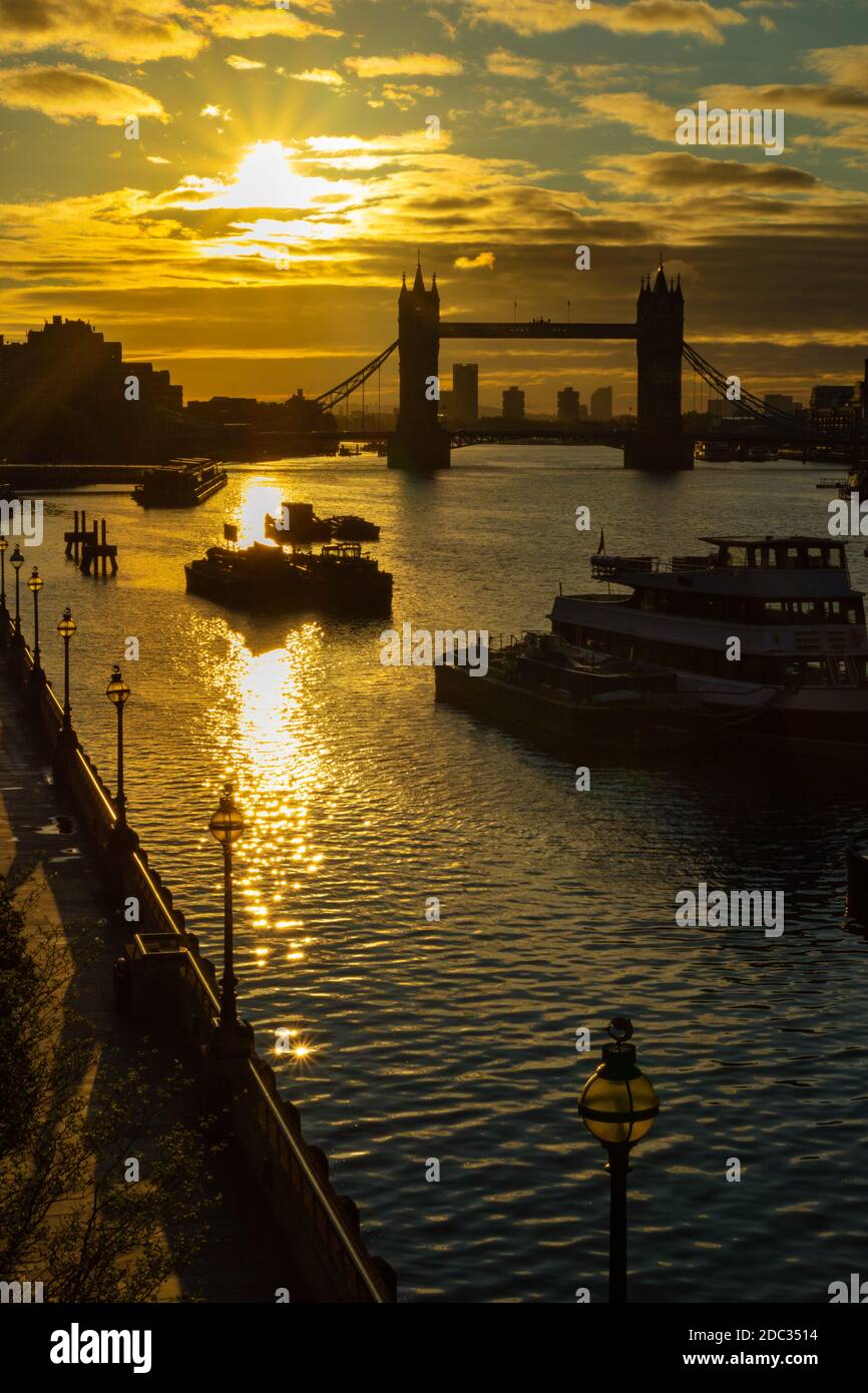 Tower Bridge in silhouette from a golden sunrise on the River Thames ...
