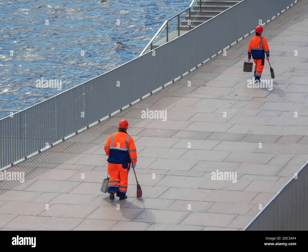 Municipal workers on a city street, janitors with a broom and a dustpan ...