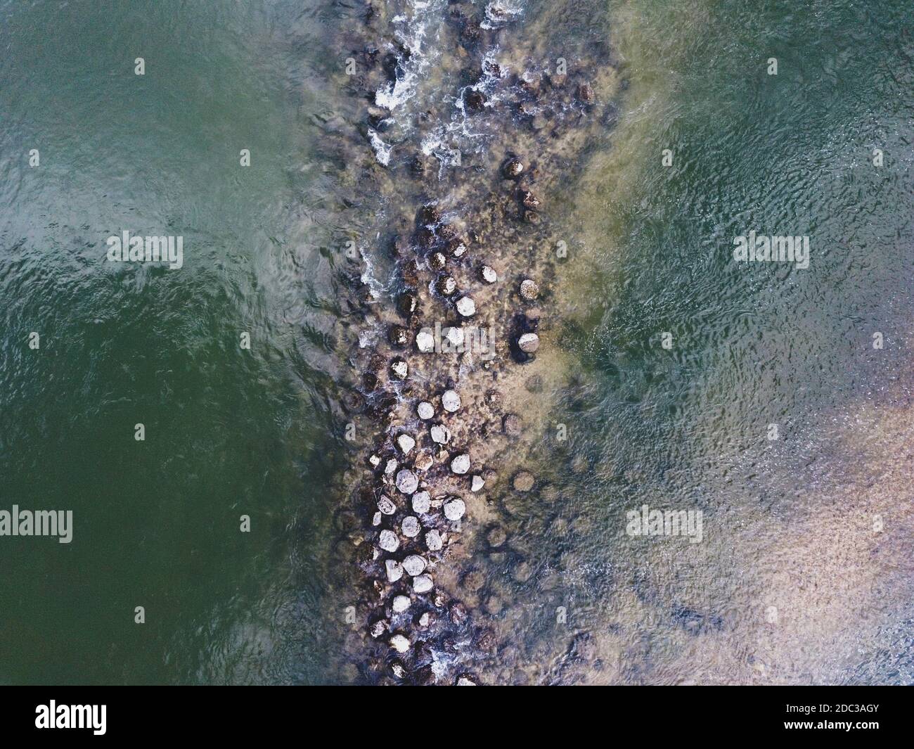 Round stone rocks standing half submerged in the midlle of the Sava ...