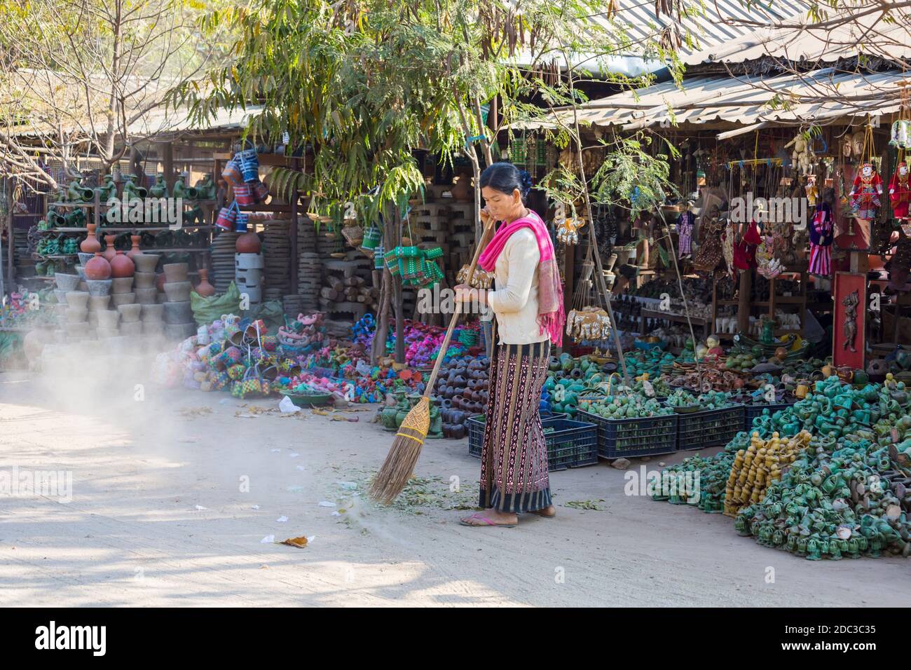 Daily life in Myanmar - local woman sweeping street by stalls at Bagan ...