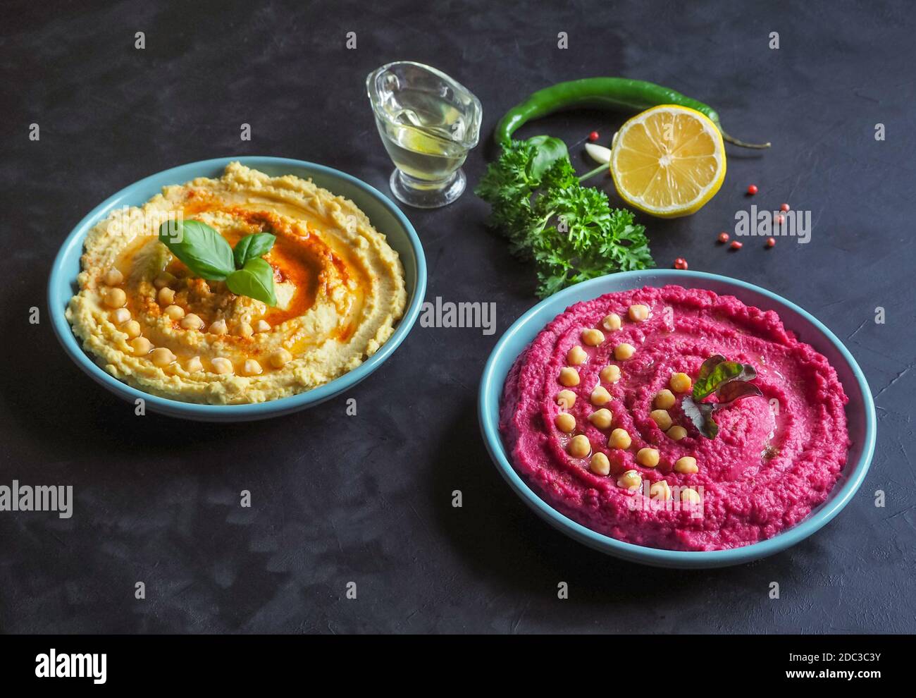 Hummus with beetroot and traditional hummus on a black kitchen table ...