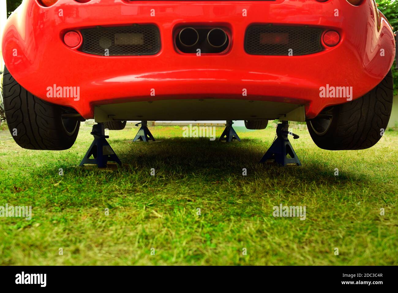 Luxury sport car lifted by up-and-under tools on grass. Fixing DIY way ...