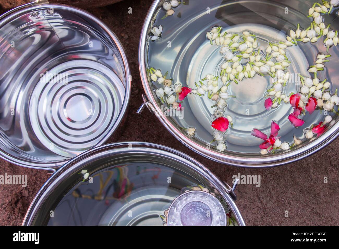 Jasmines and rose petals floating in large stainless bucket for ...