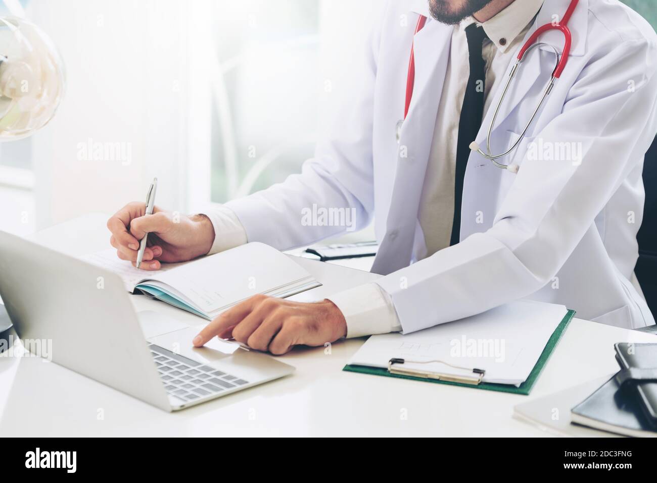 Doctor working on laptop computer at office table in the hospital ...