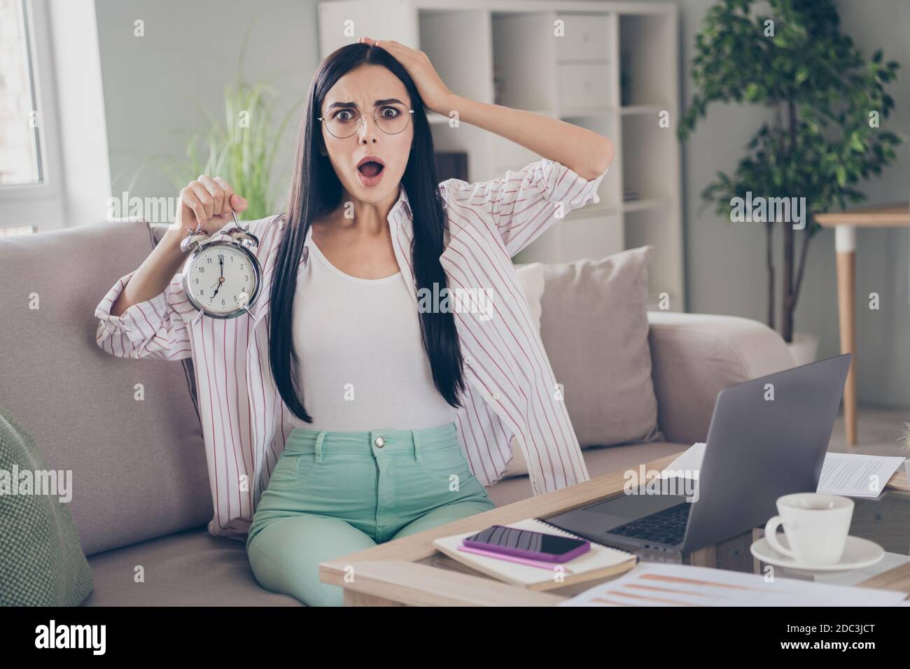 Portrait photo of shocked nervous brunette woman keeping alarm clock ...