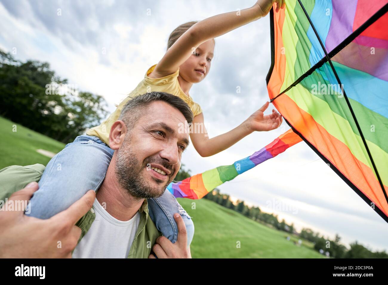 Happy father carrying cute little daughter on his shoulders while she ...