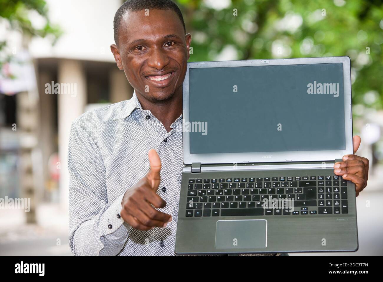 young man standing in shirt with laptop watching camera smiling Stock ...