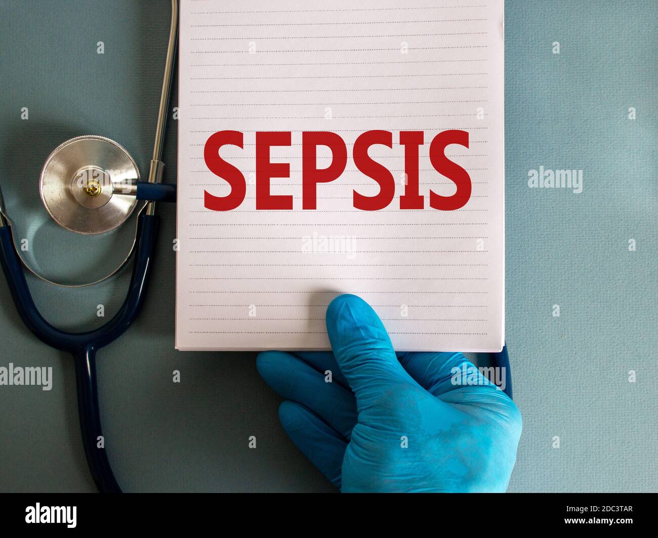Hand in blue glove, white card with word 'sepsis' and stethoscope ...