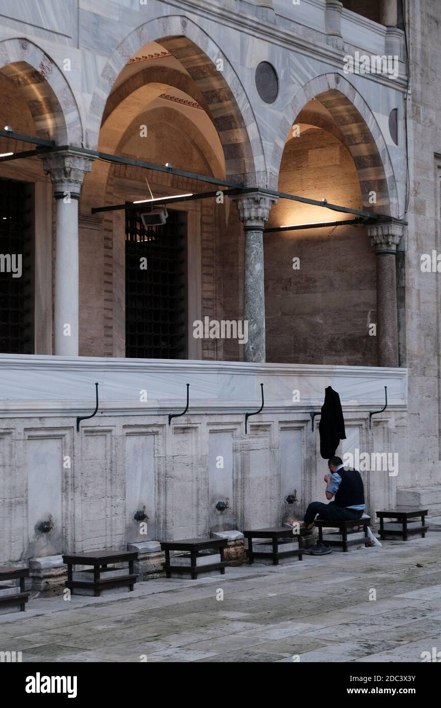 A Muslim man washing hands and feet before prayer at Suleymaniye Mosque ...