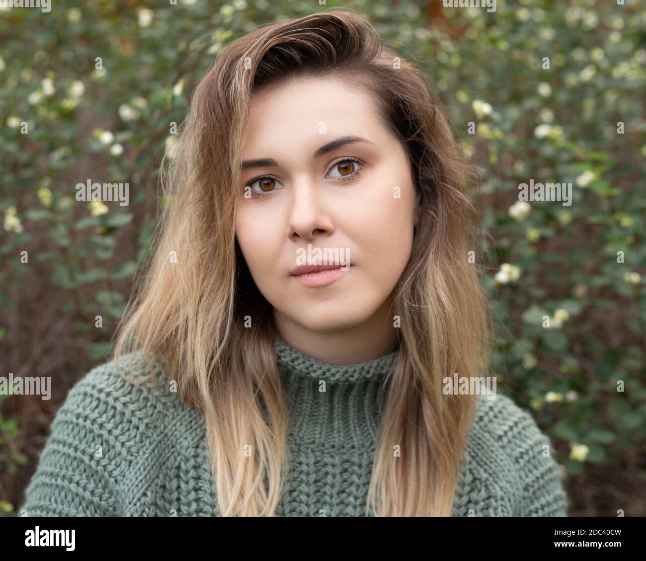 Young beautiful 27 years old woman in a sweater, standing outdoors ...