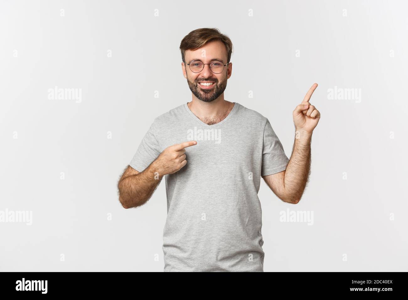 Cheerful bearded man smiling, pointing fingers at upper right corner ...