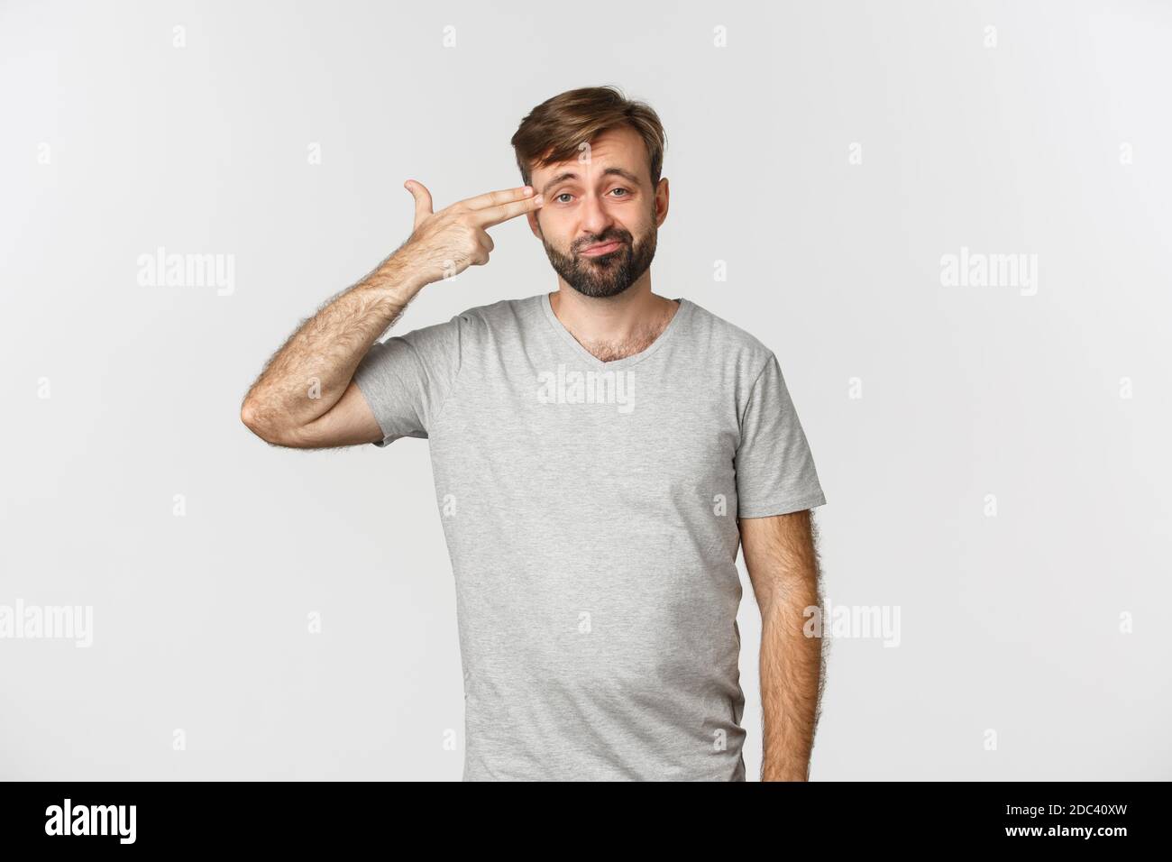 Portrait of distressed and tired guy making finger gun sign and looking ...