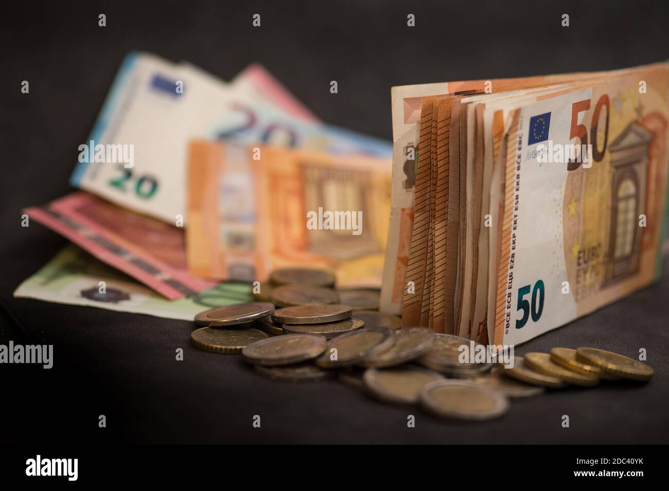 a stack of 50 euro money and many euro coins on a dark background Stock ...