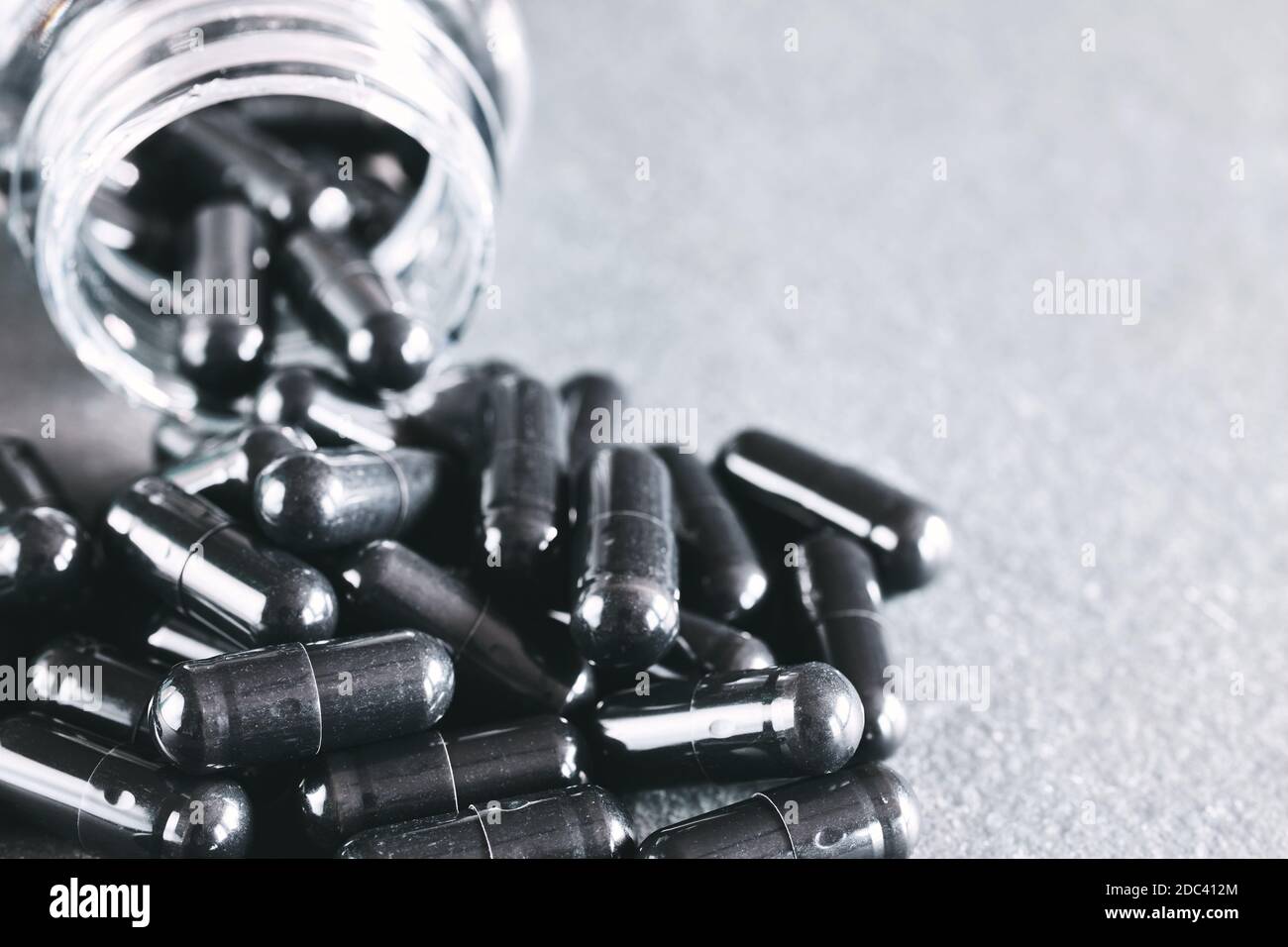 Close up picture of black capsules spill out of container, selective ...