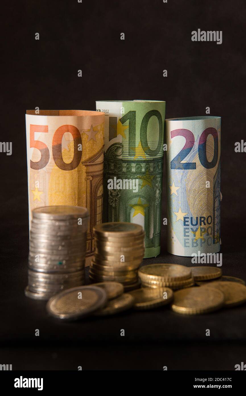 Euro banknotes rolls and stacked coins on a dark background Stock Photo ...