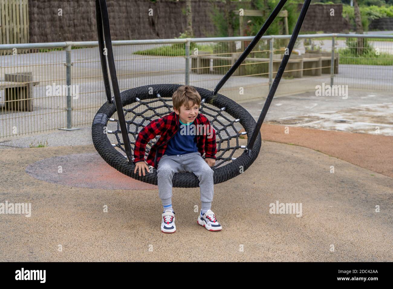Happy boy playing with swing cobwebs in the playground. Children ...