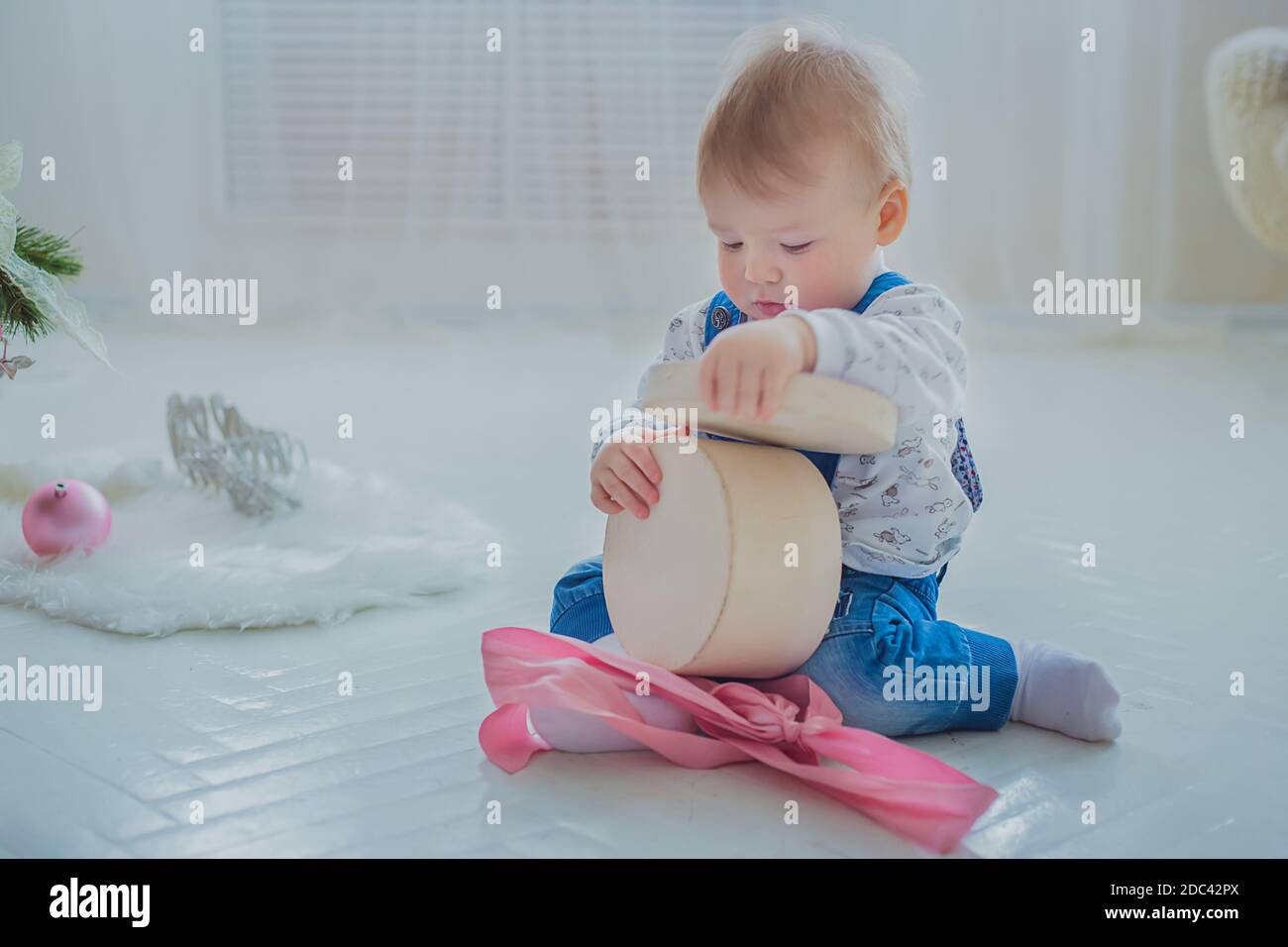 Portrait of little boy playing with empty gift box in bright white room ...