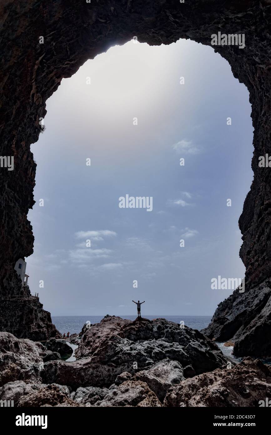 stone arch by the sea where you see a man with open arms Stock Photo ...