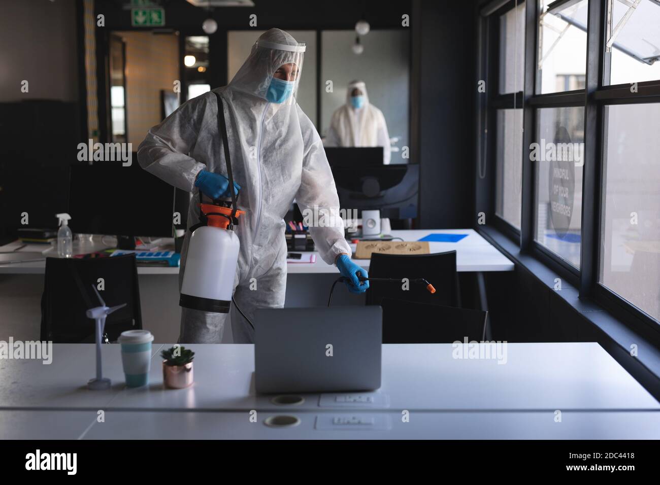 Health worker wearing protective clothes cleaning office using ...