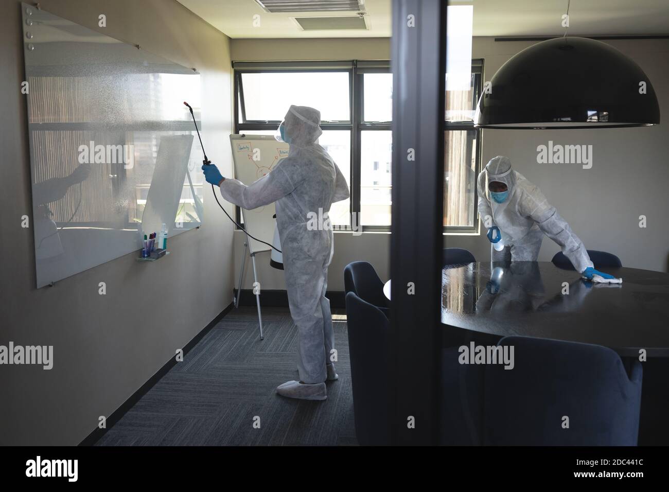 Team of health workers wearing protective clothes cleaning office using ...