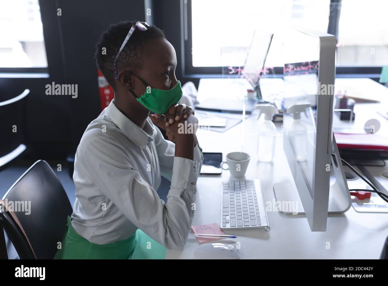 African american woman wearing face mask looking at her computer screen ...