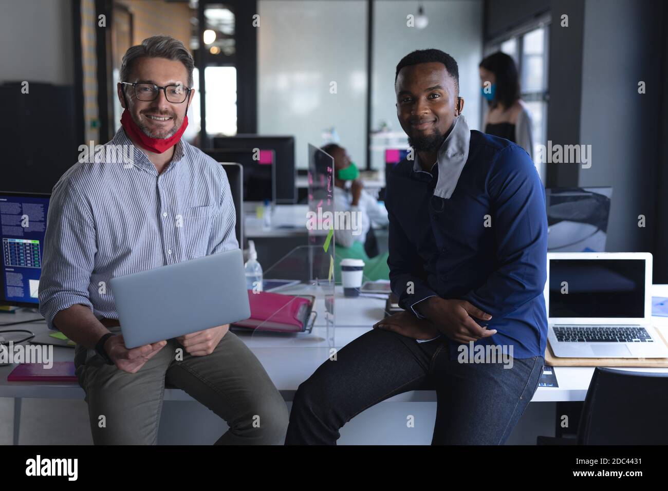 Portrait of diverse male colleagues with face masks around their neck ...
