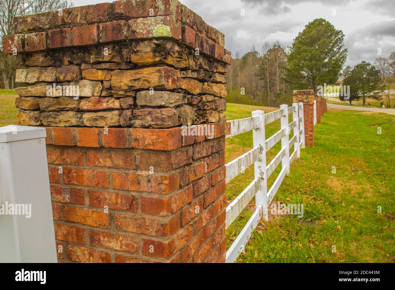 Brick fence post and a white wooden fence along the road side Stock ...