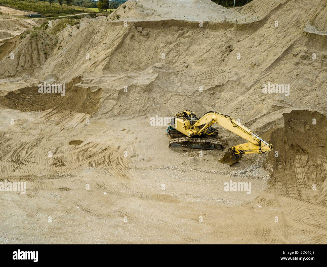 Aerial view from above of digger in pit. Excavator works in quarry ...