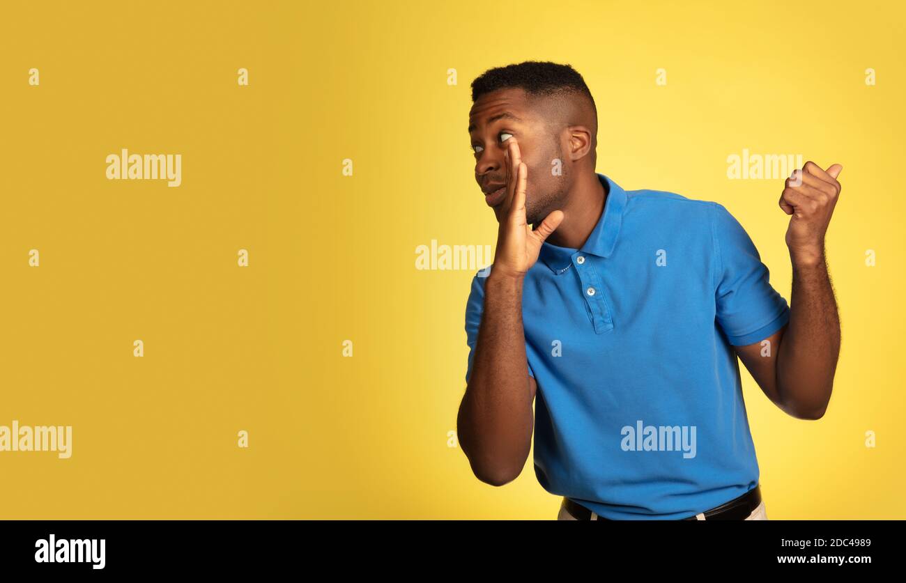 Whispering a secret, pointing. Young african-american man's portrait ...