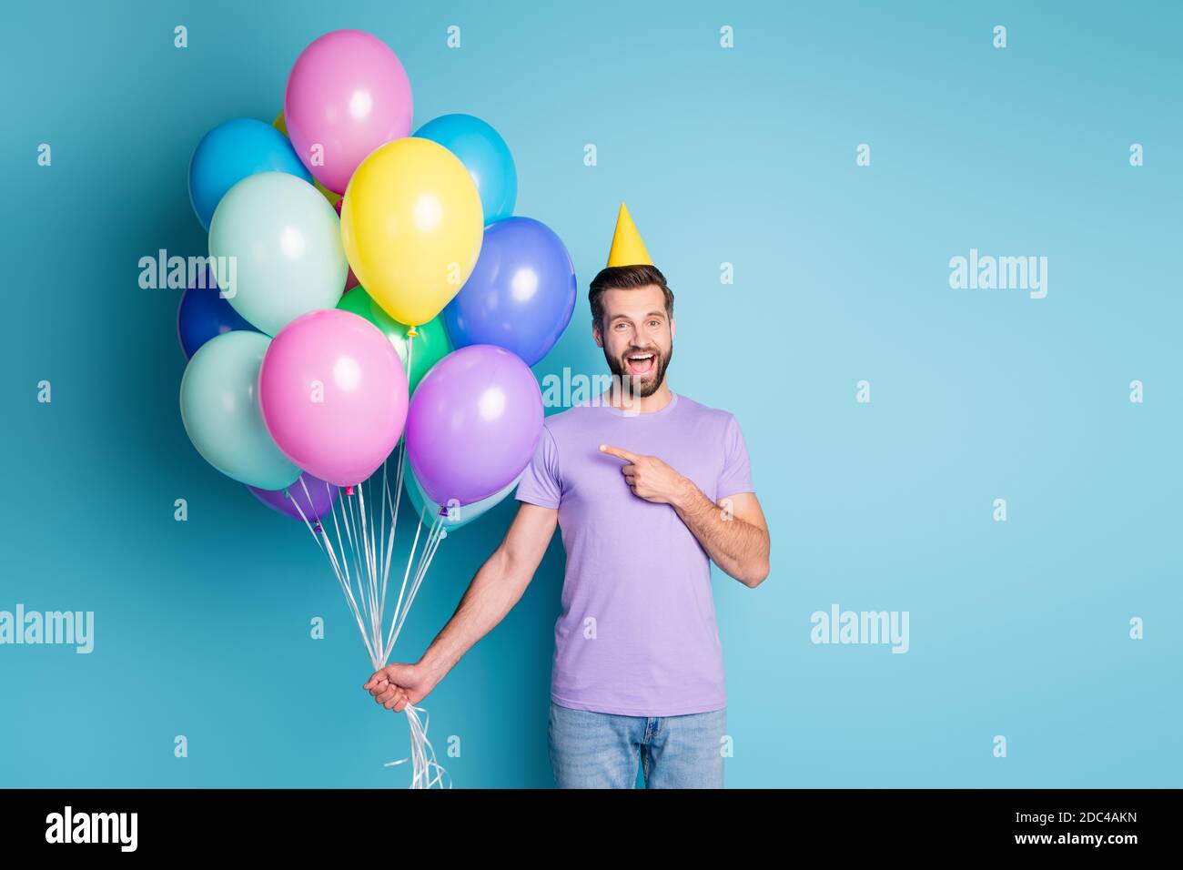 Photo portrait of cheerful happy man pointing at balloons in festive ...