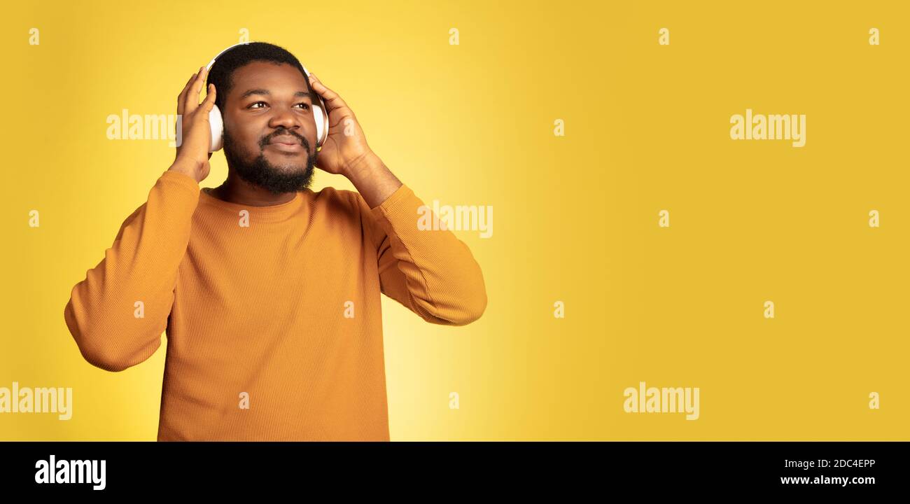 Joyful, flyer. Young african-american man's portrait isolated on yellow ...