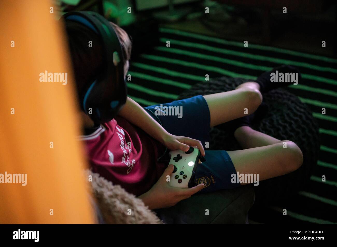 A young boy pictured playing an XBOX one console, being lit by the ...