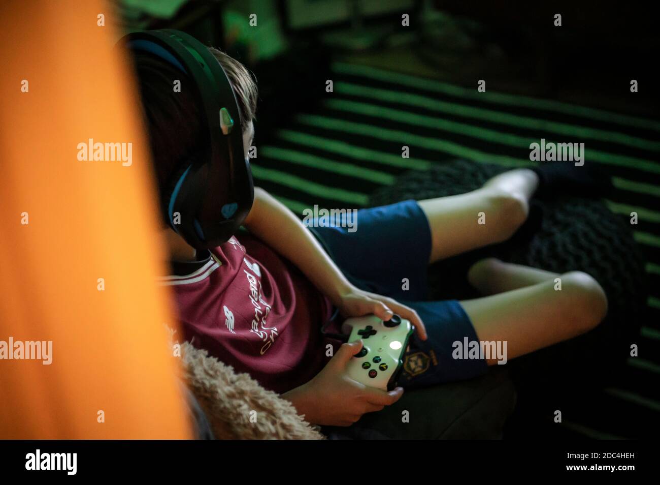 A young boy pictured playing an XBOX one console, being lit by the ...