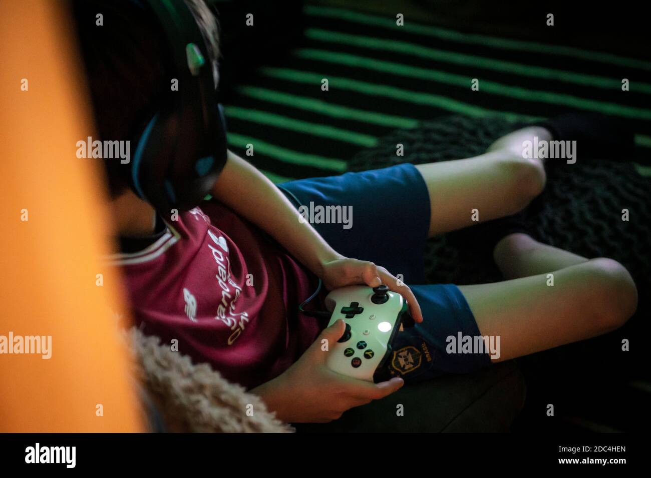 A young boy pictured playing an XBOX one console, being lit by the ...