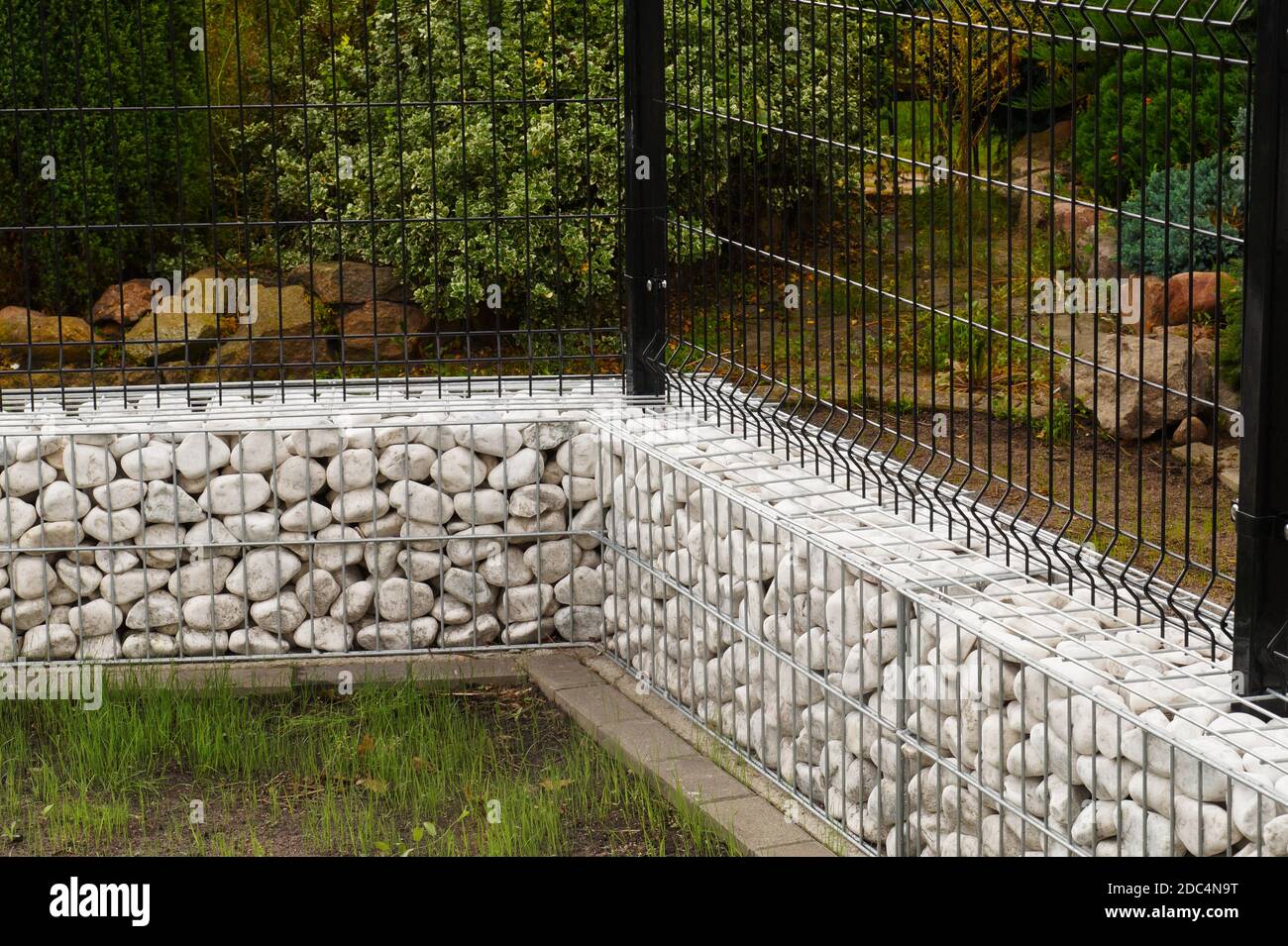 A steel fence combined with a low wall made of gabions filled with ...