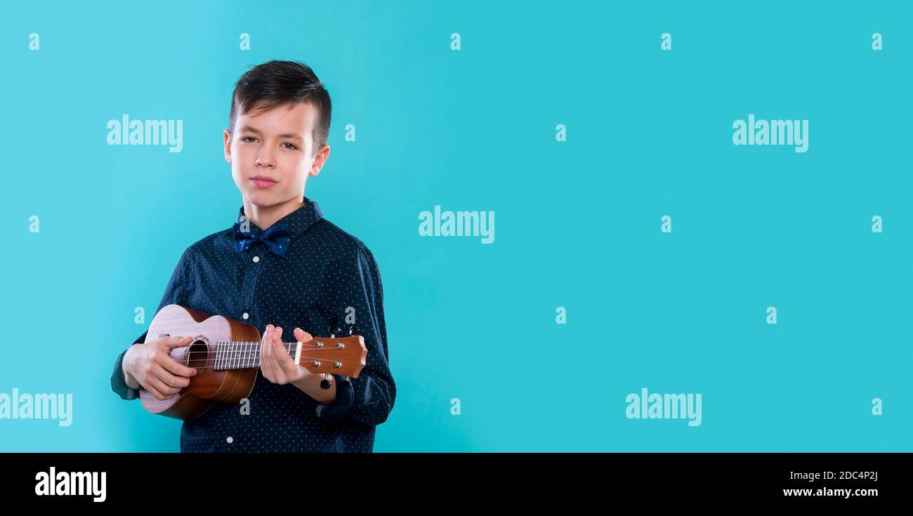 Boy with ukulele guitar on blue background. Kid music concept Stock ...