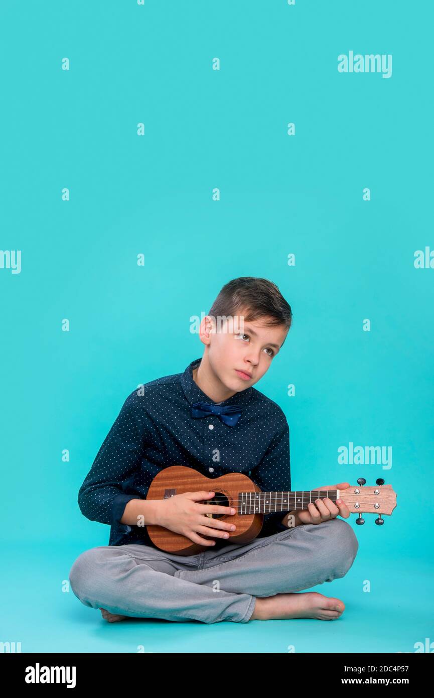 Boy with ukulele guitar on blue background. Kid music concept Stock ...