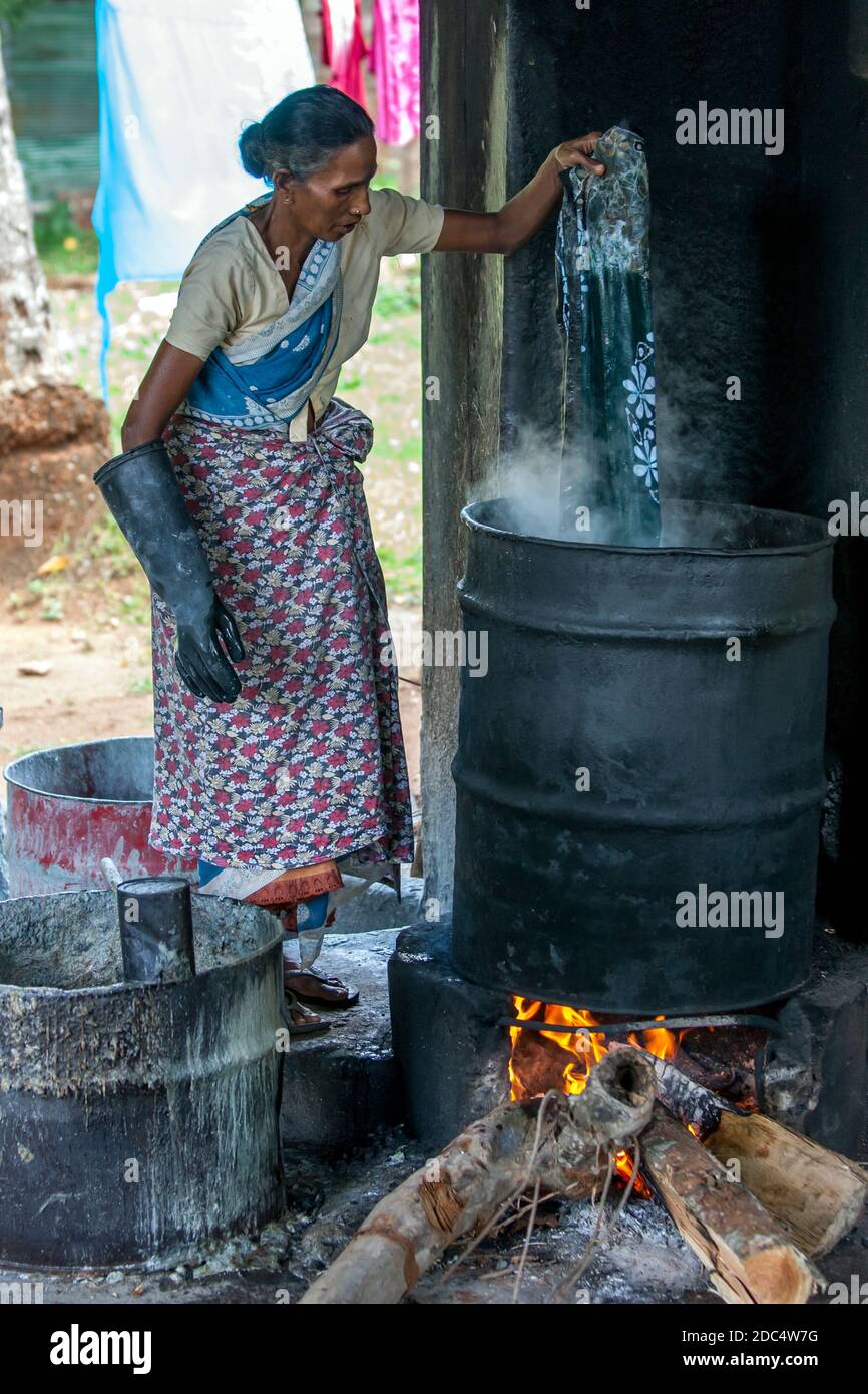 A worker melts the wax off a batik in a drum of boiling water after the ...
