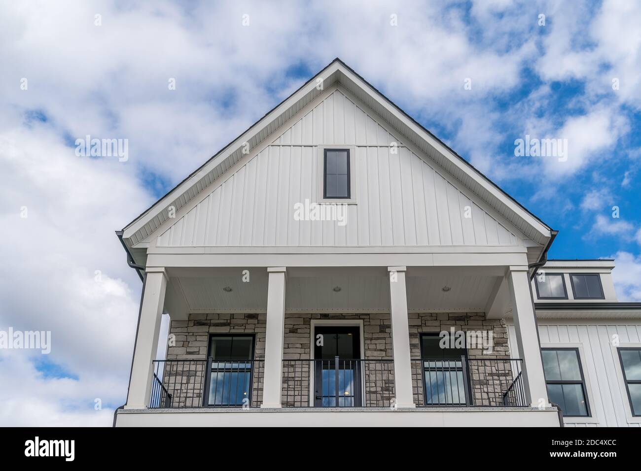 Covered porch on a new single family home with black brass rails, white ...