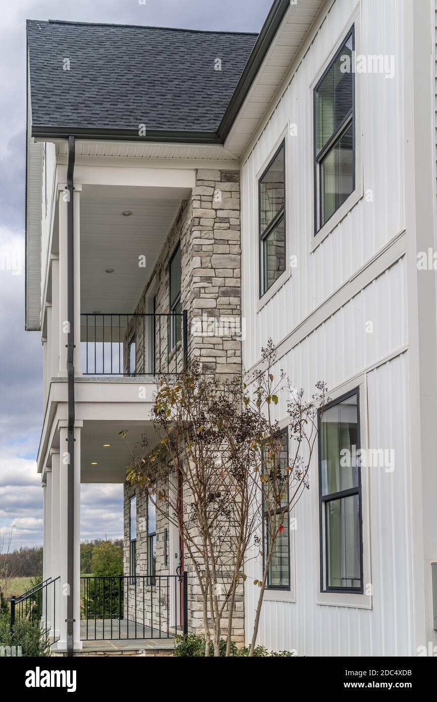 Covered porch on a new single family home with black brass rails, white ...