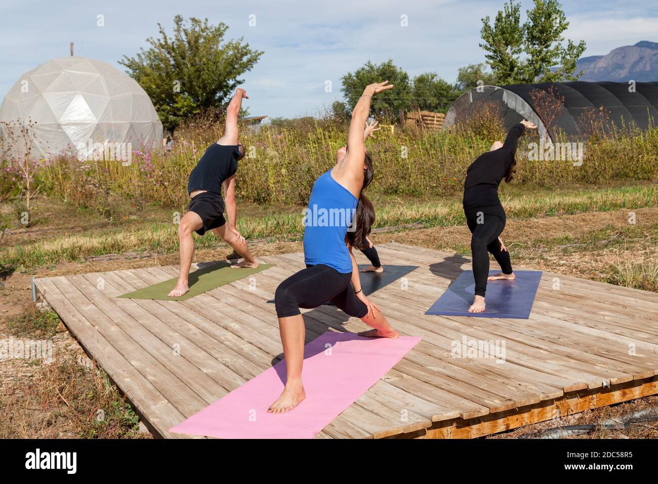 A small group of people participating in an afternoon outdoor yoga ...