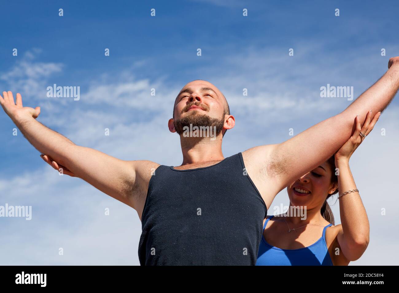 A yoga instructor gives tips to a student at an outdoor afternoon yoga ...