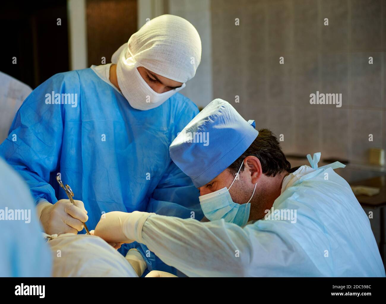 Surgery. Side view of surgeon performing the operation, next to his ...