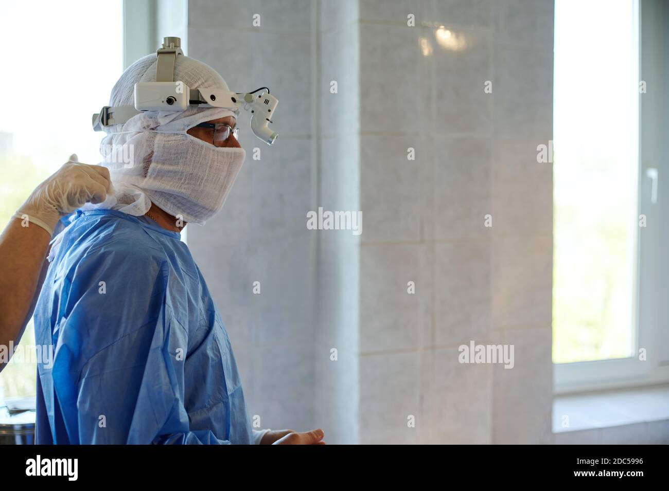 A nurse assists chief surgeon in putting on a protective uniform Stock ...