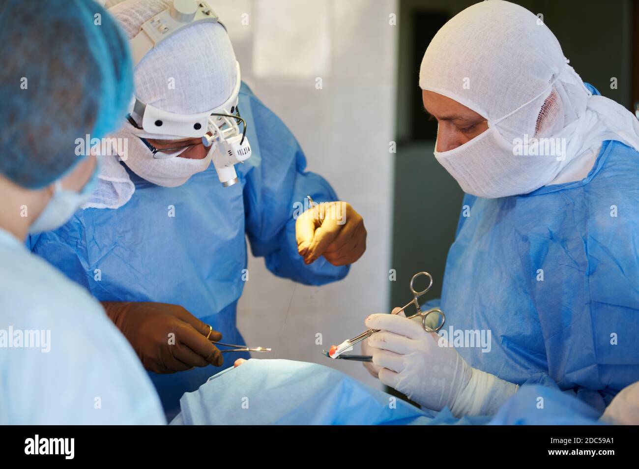 Surgery. Team of surgeons in blue suits stitch up the wound Stock Photo ...