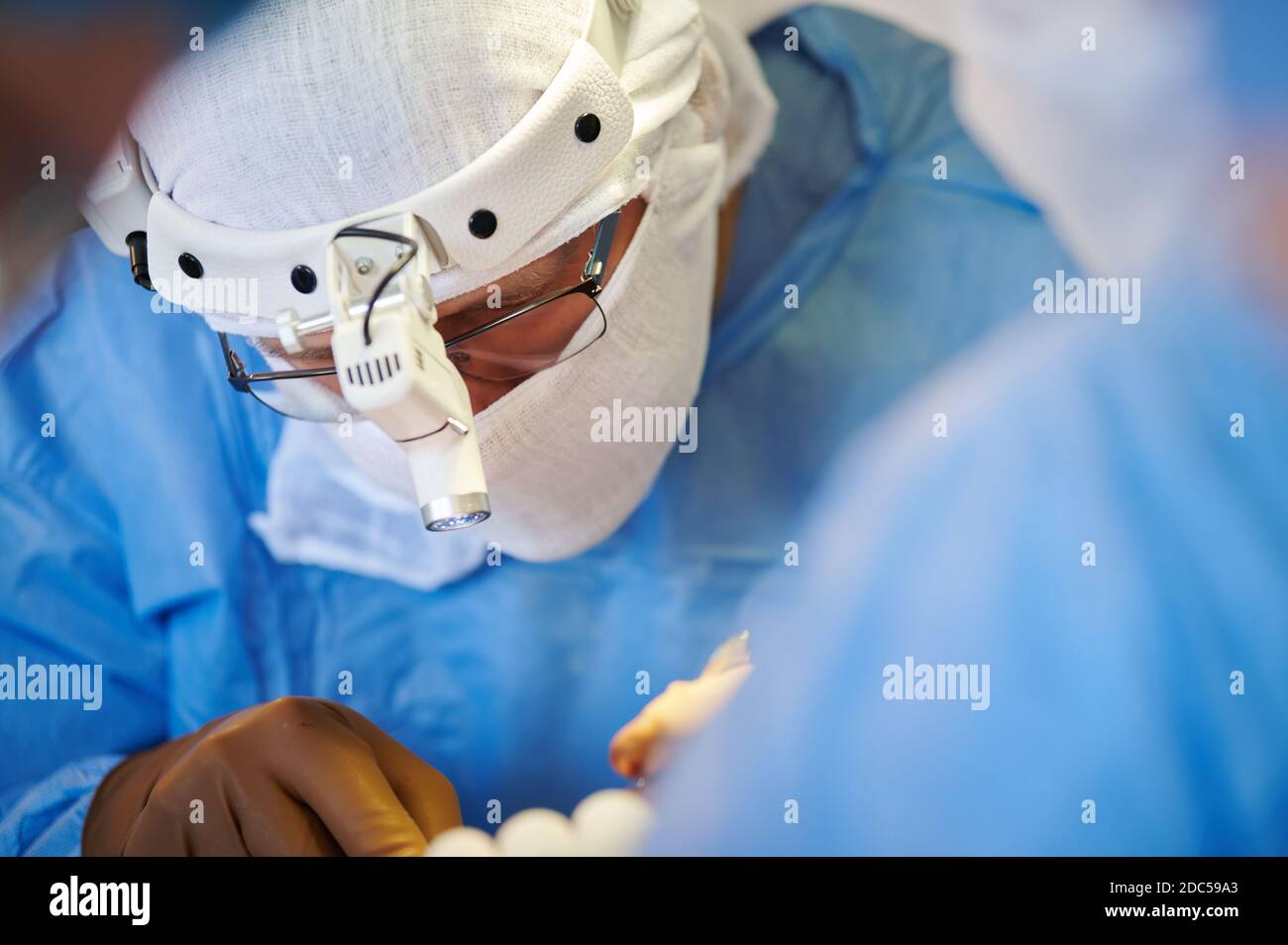 Surgery. Close-up portrait of surgeon, with a flashlight on his head in ...