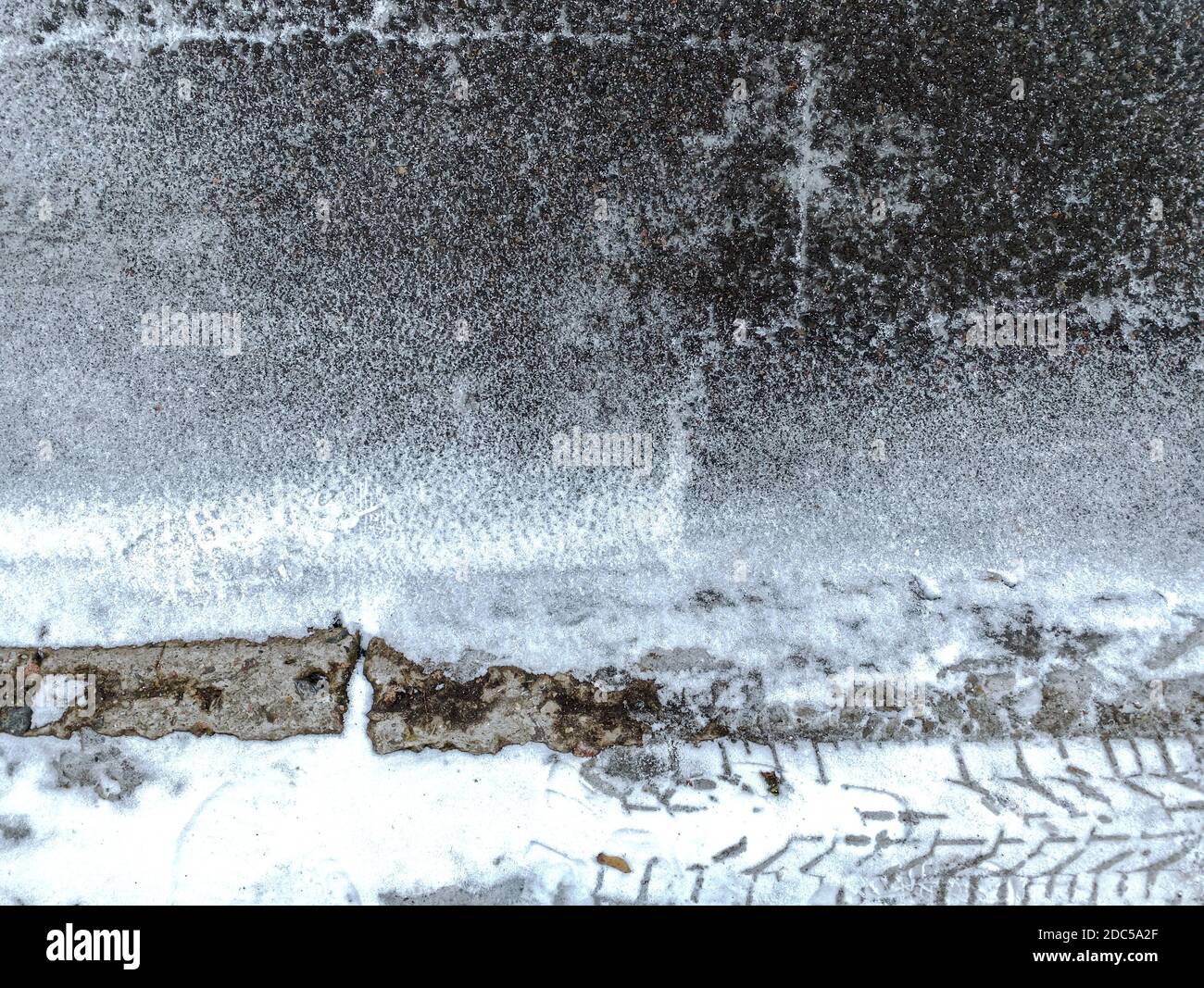 snowy winter road with thin layer of snow and imprints of tire tracks ...