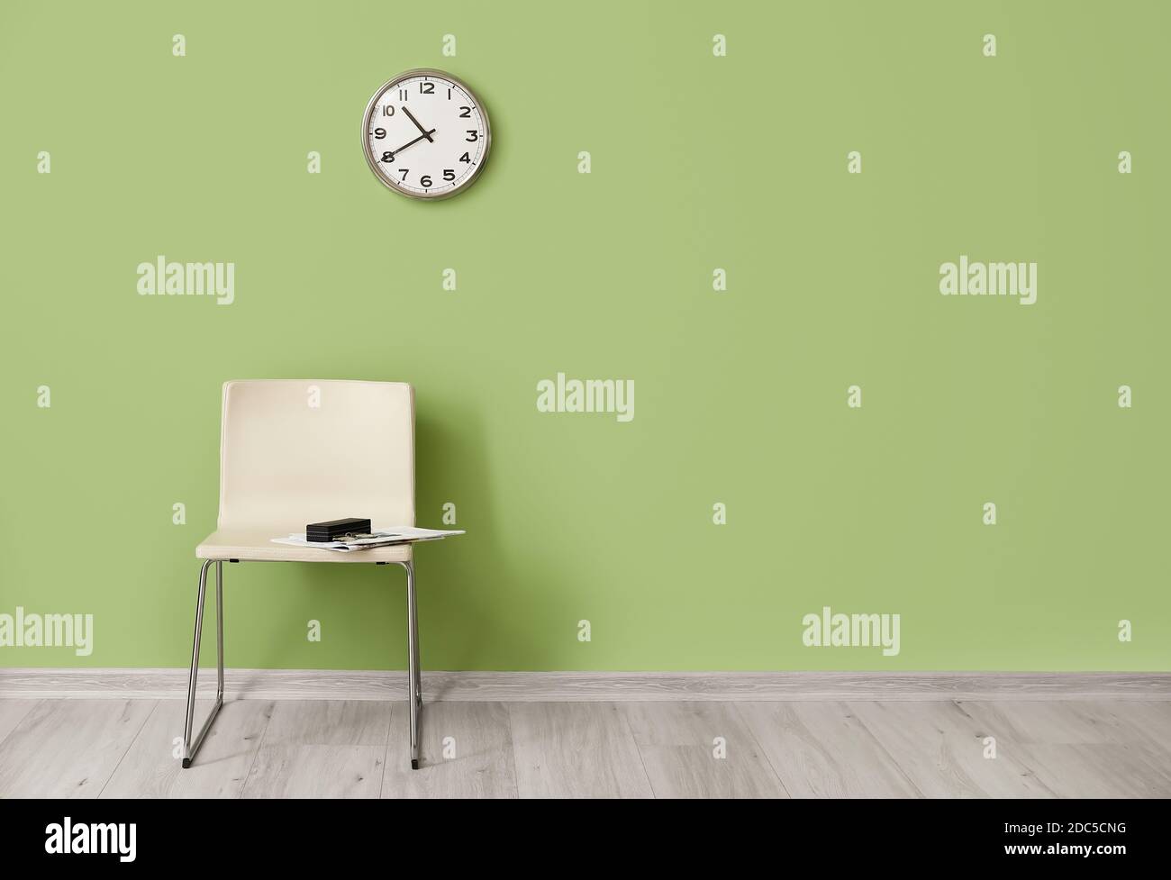 Chair near color wall with clock Stock Photo - Alamy