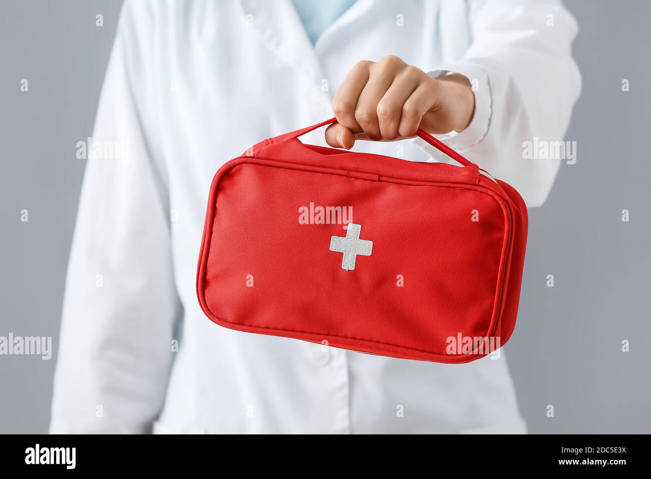 Doctor with first aid kit on grey background Stock Photo - Alamy