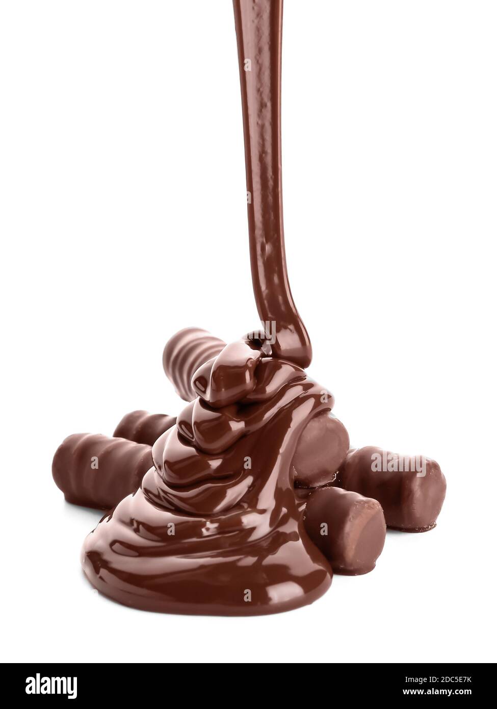 Pouring of melted chocolate on sweet candies against white background ...